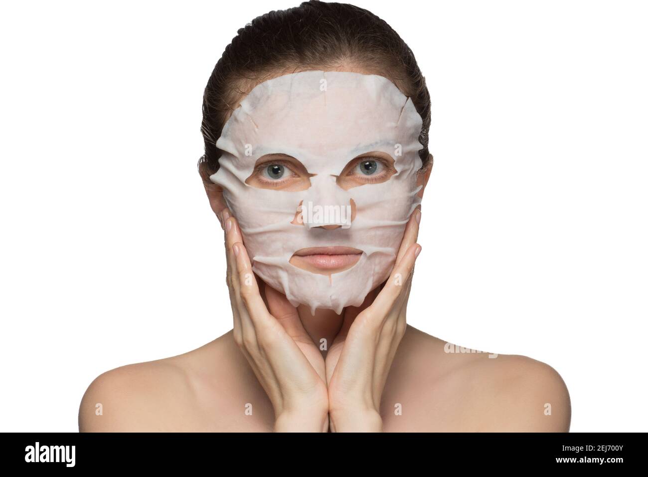 Beautiful young woman is applying a cosmetic tissue mask on a face on a ...