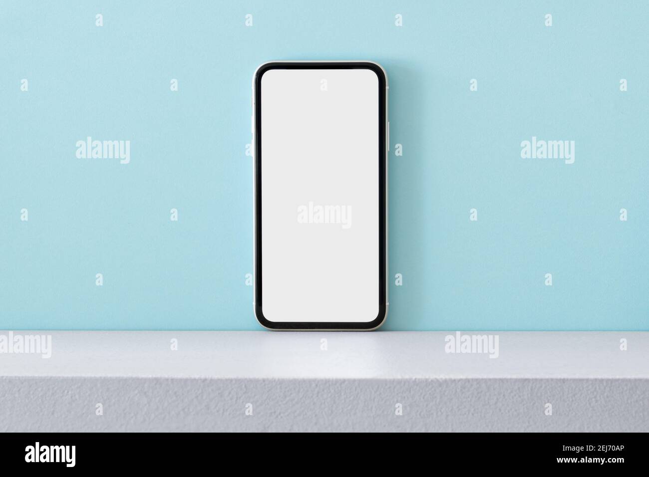 Modern mobile phone with empty screen placed on shelf on light blue ...