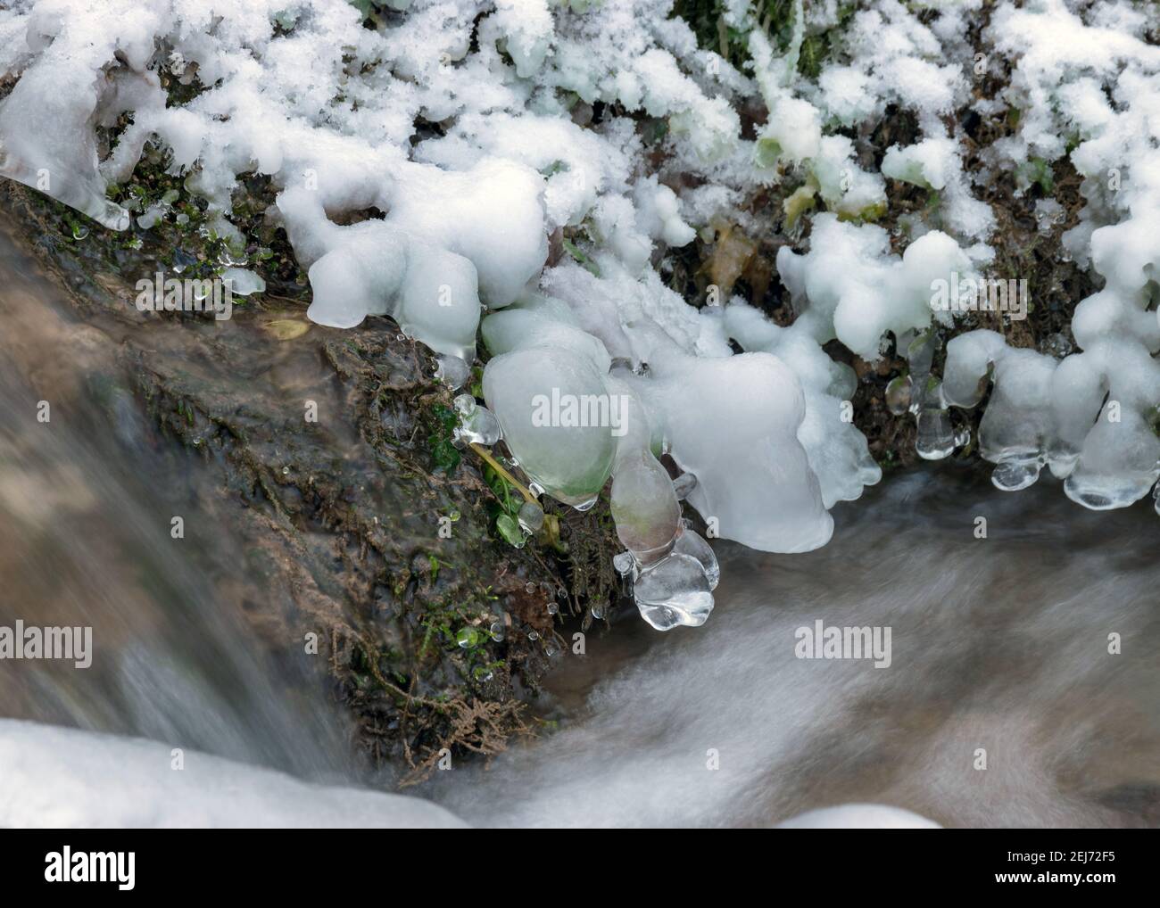 frozen fast flowing spring water, icy rocks and water stream, frosty ...