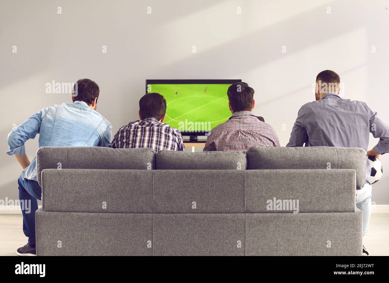 Back view of young men sitting on comfortable sofa and watching ...