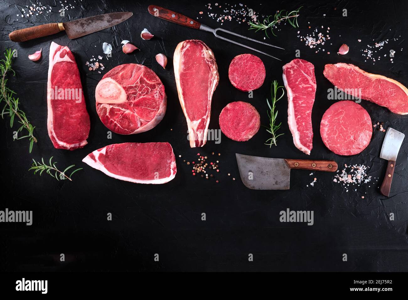 Meat cuts variety with knives and seasoning, overhead flat lay shot ...