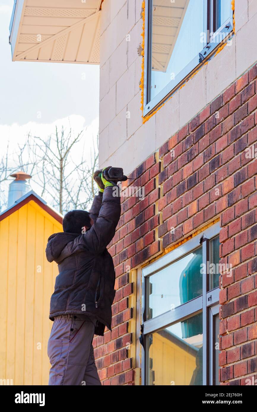 A man works with a drill, attaches thermal panels made of clinker to ...