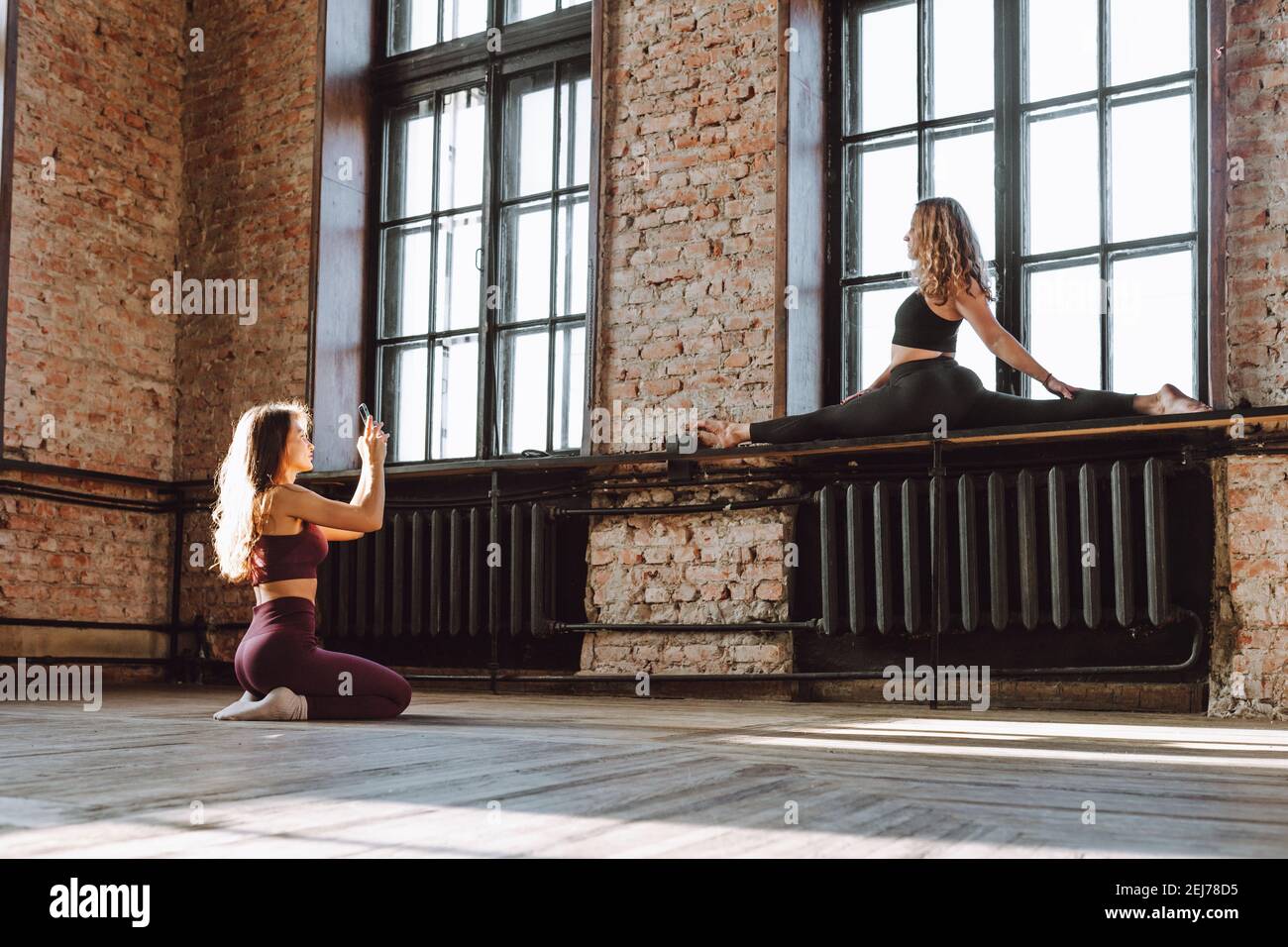 Two female friends take photo after hard workout loft style studio ...