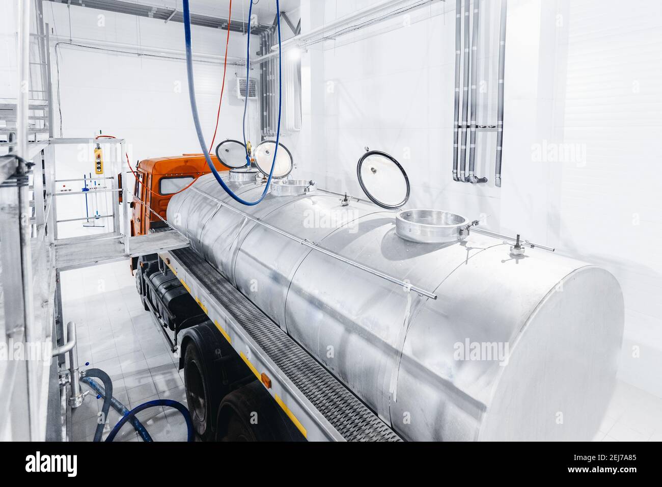 Milk tanker truck pumps products into steel storage tanks, dairy ...