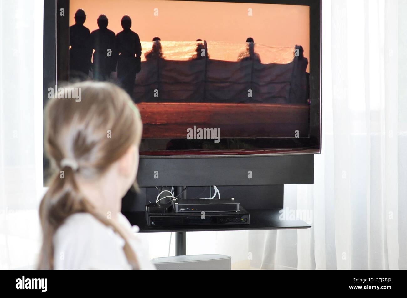 White European girl sitting (siting) in front of TV and watching a ...