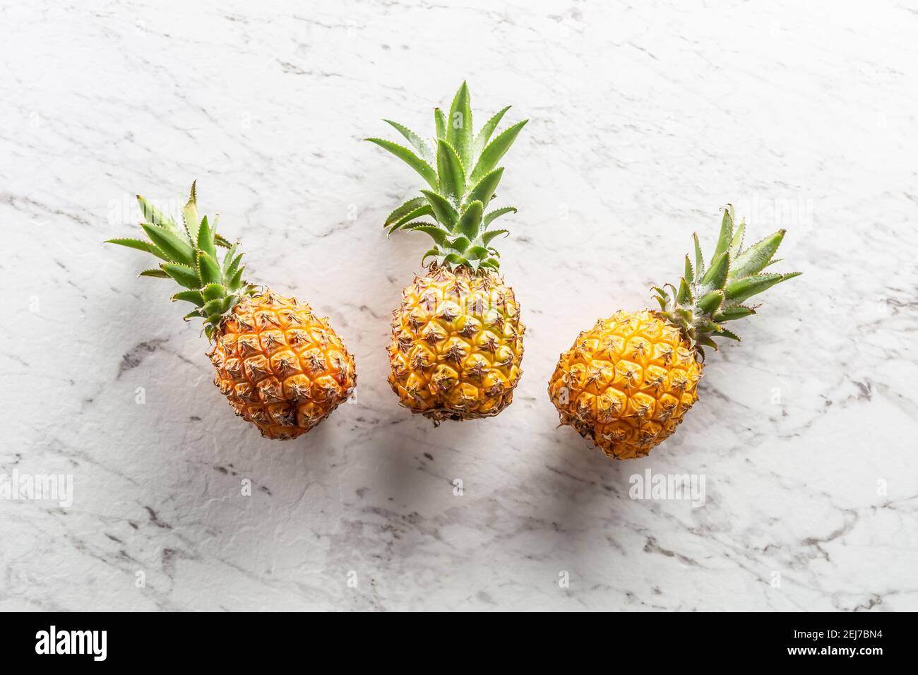 Three fresh whole pineapples with leaves on a marble surface Stock ...
