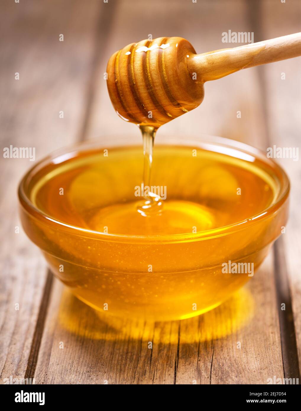 pouring honey into bowl on a wooden background Stock Photo - Alamy