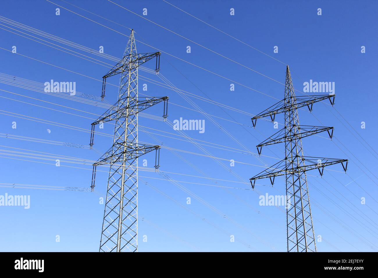 Two Electricity pylons in the blue sky. Energy transition Environment ...