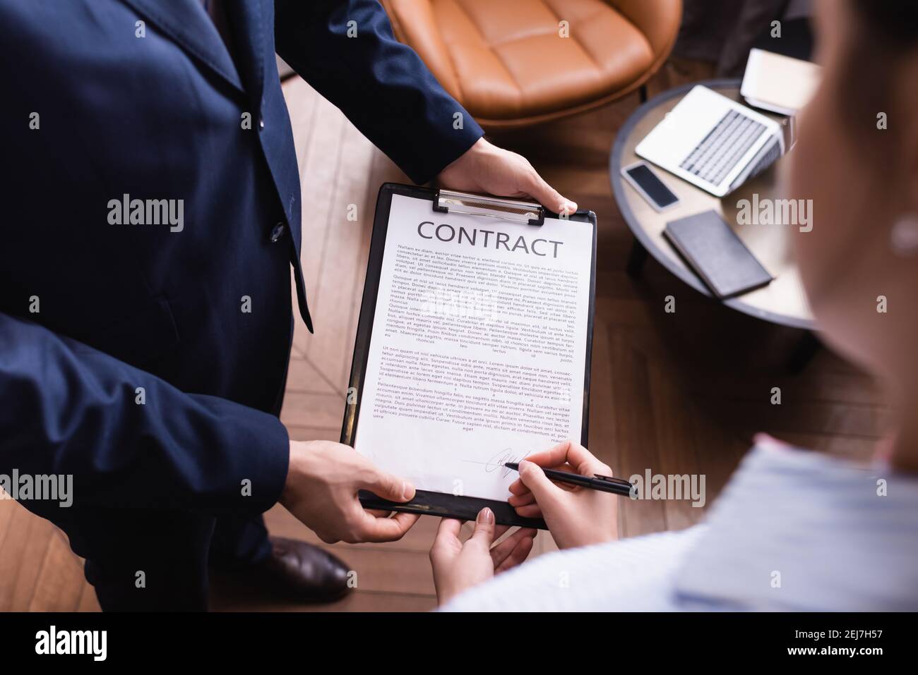 High angle view of businesswoman singing contract near businessman ...