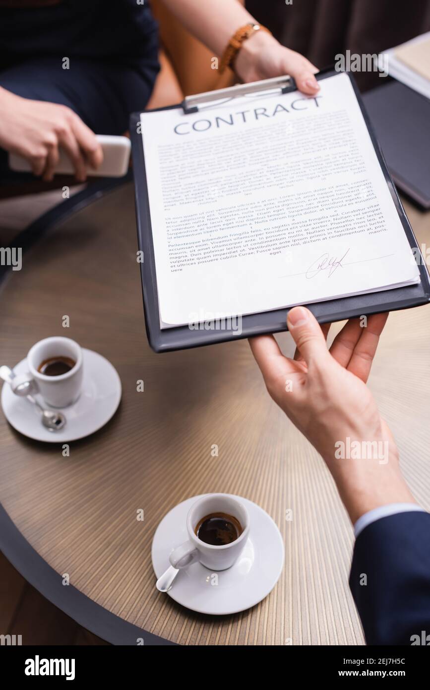 Cropped view of businessman taking contract from businesswoman near ...