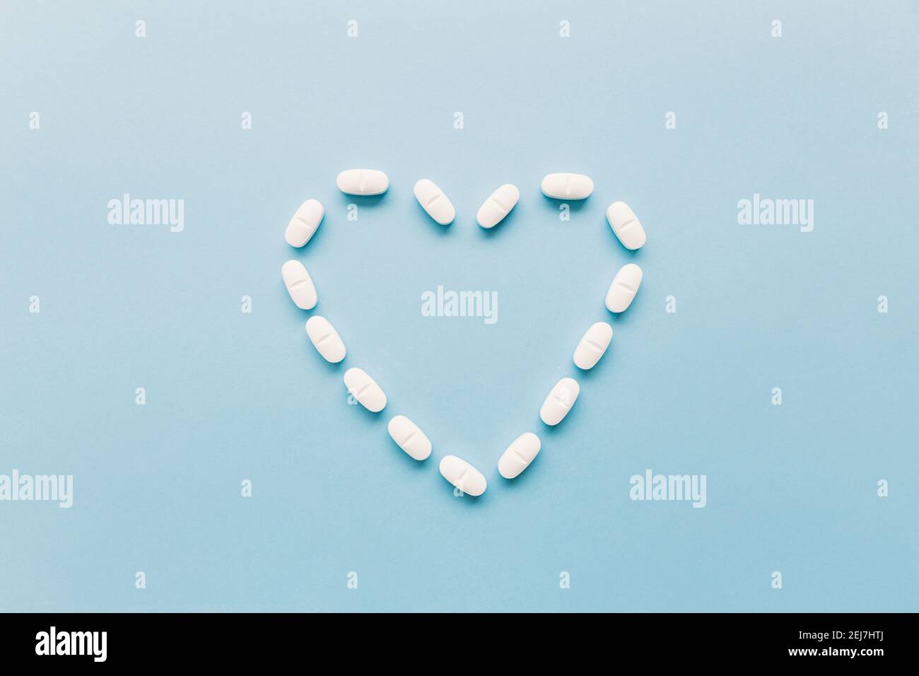 heart-shaped medicine pills on a blue background Stock Photo - Alamy