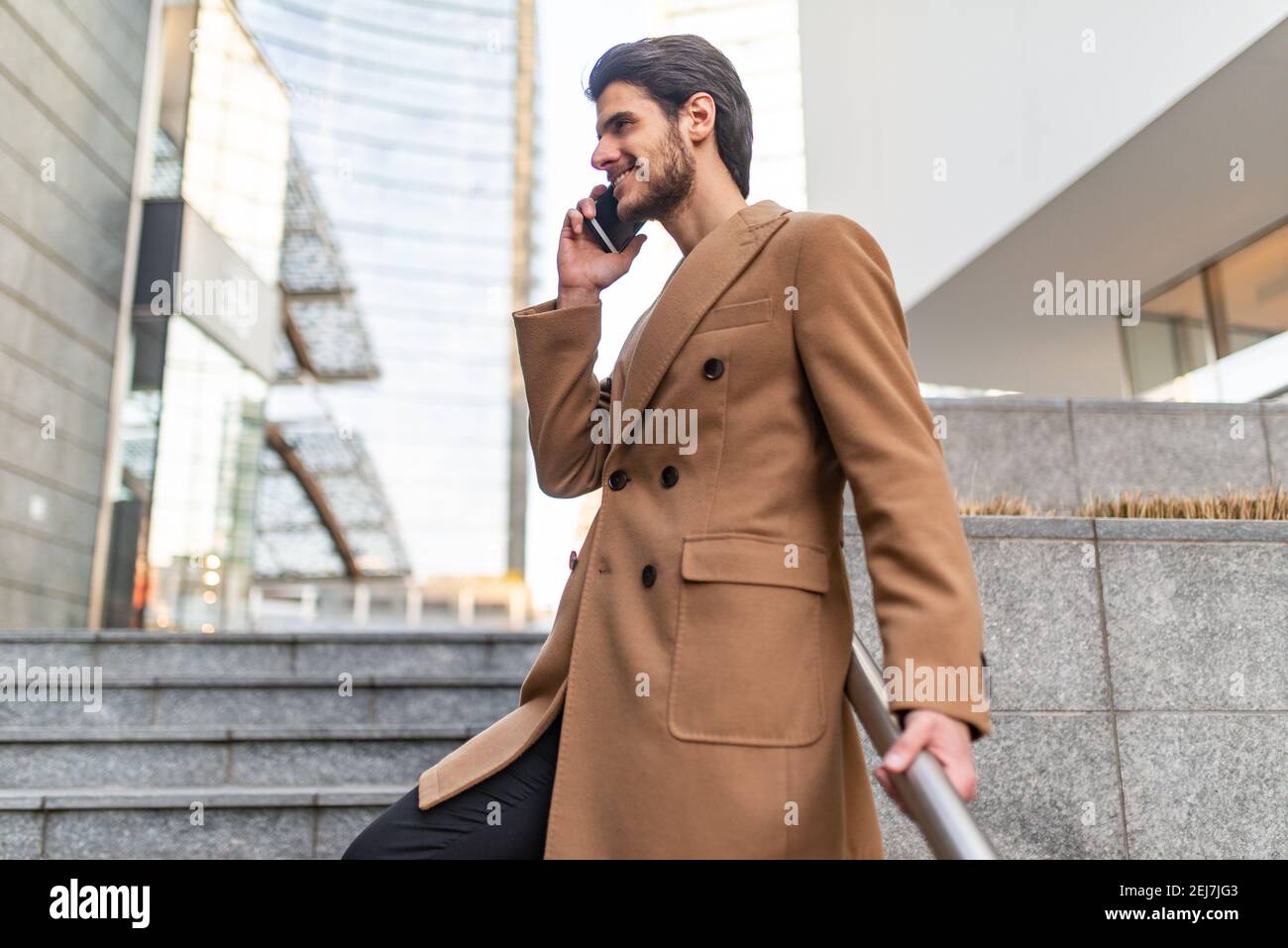 Smiling man talking on the phone while walking down a stair Stock Photo ...
