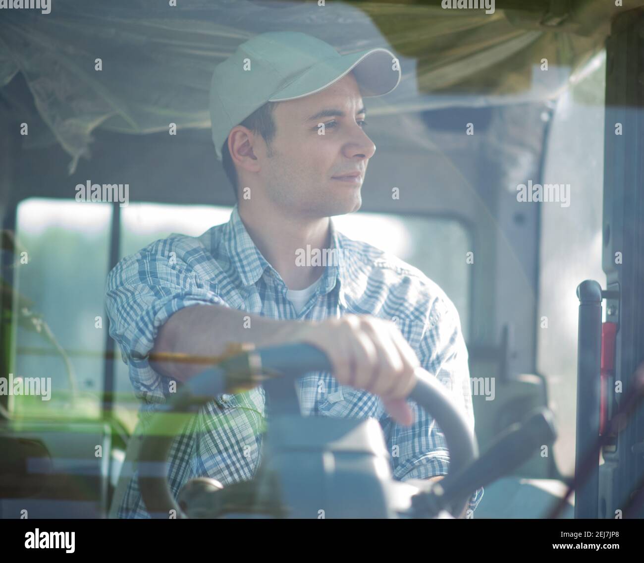 Smiling young farmer driving a tractor Stock Photo - Alamy