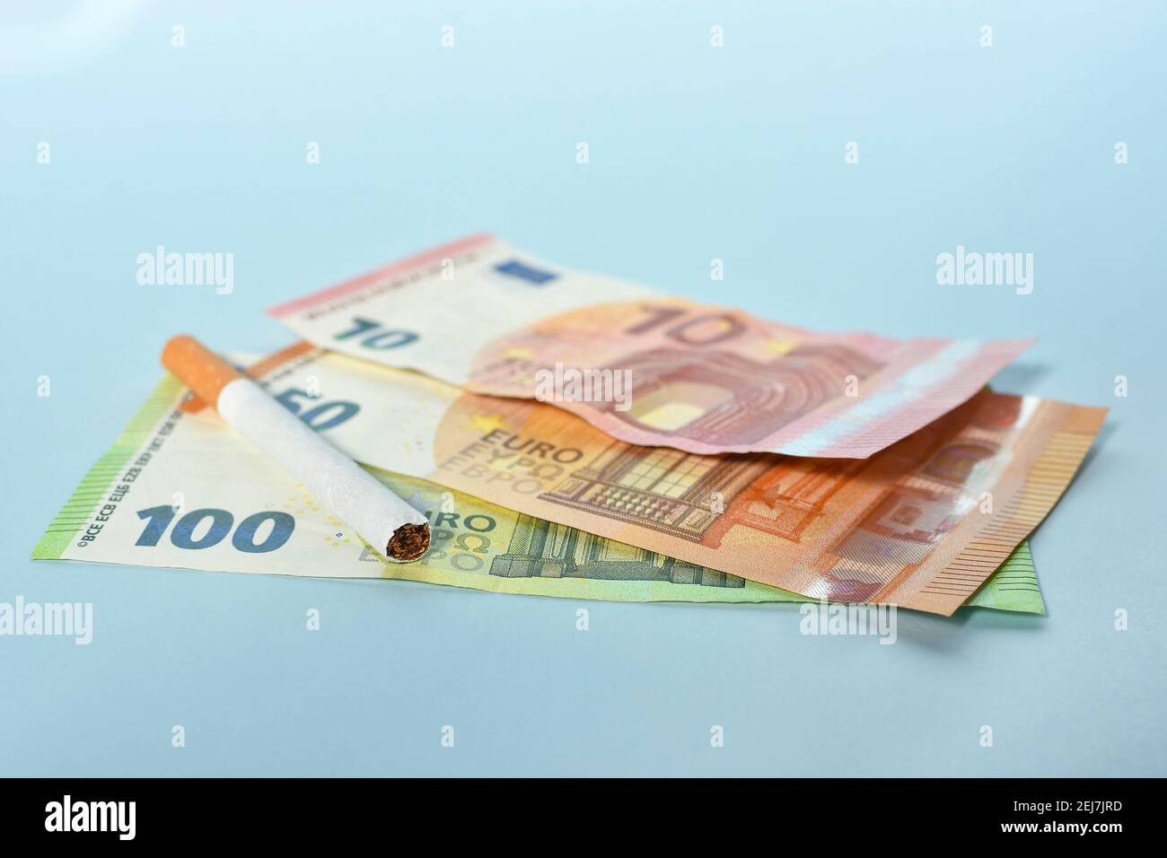 Cigarettes and money on blue background. Euro banknotes and coins, cost ...