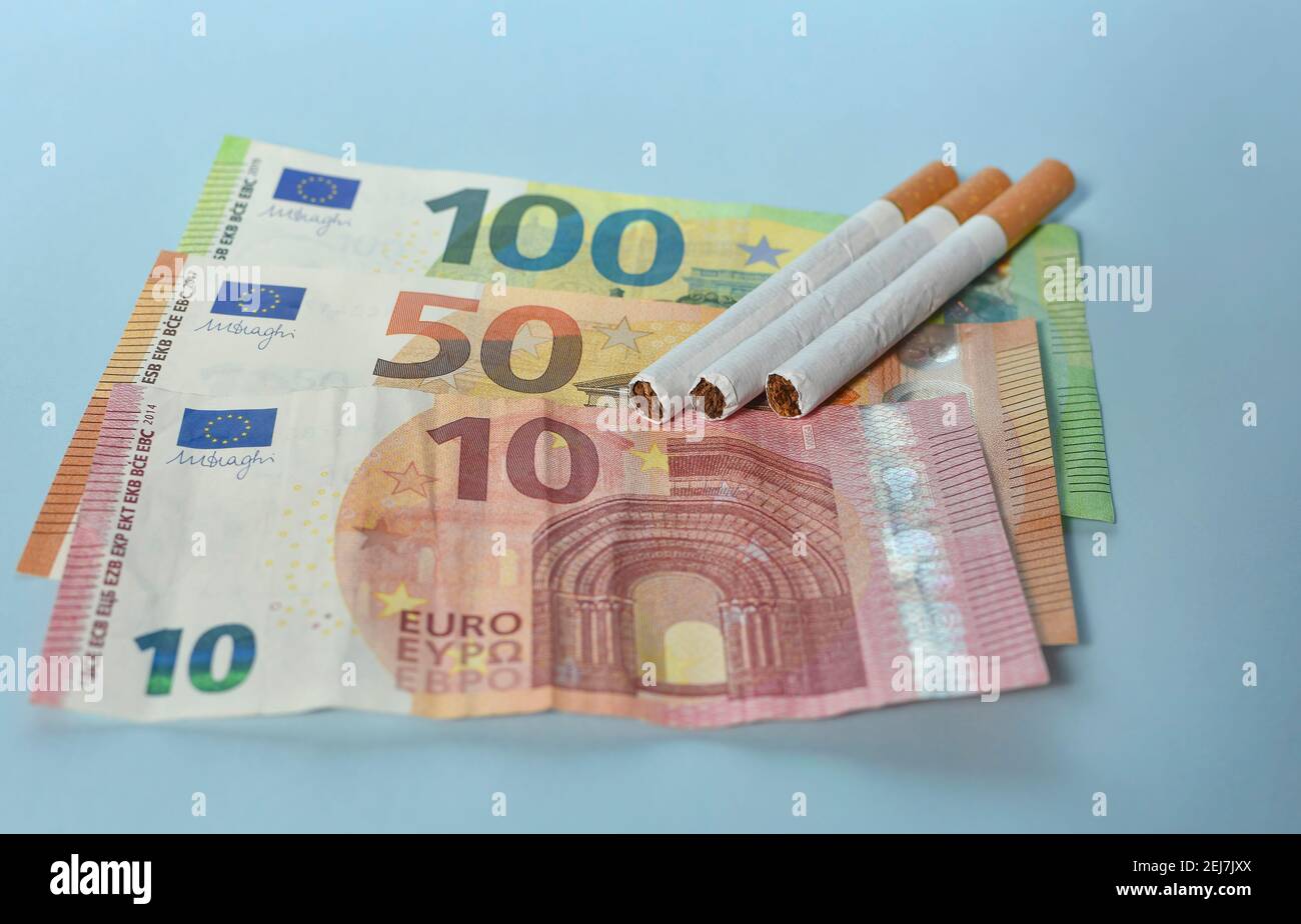 Cigarettes and money on blue background. Euro banknotes and coins, cost ...
