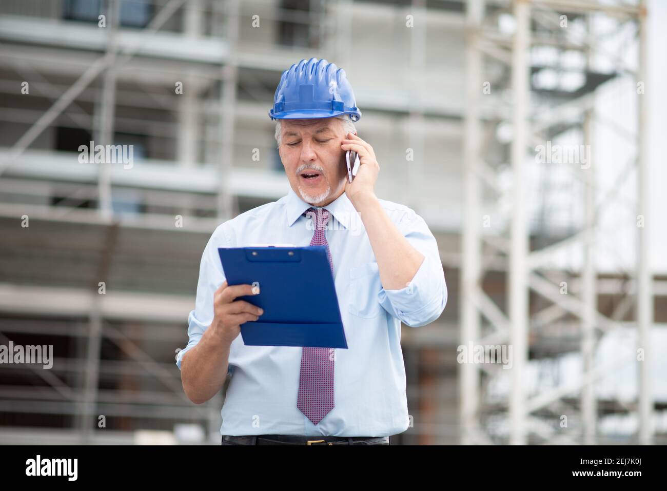 Architect site manager talking on the cellphone in front of ...