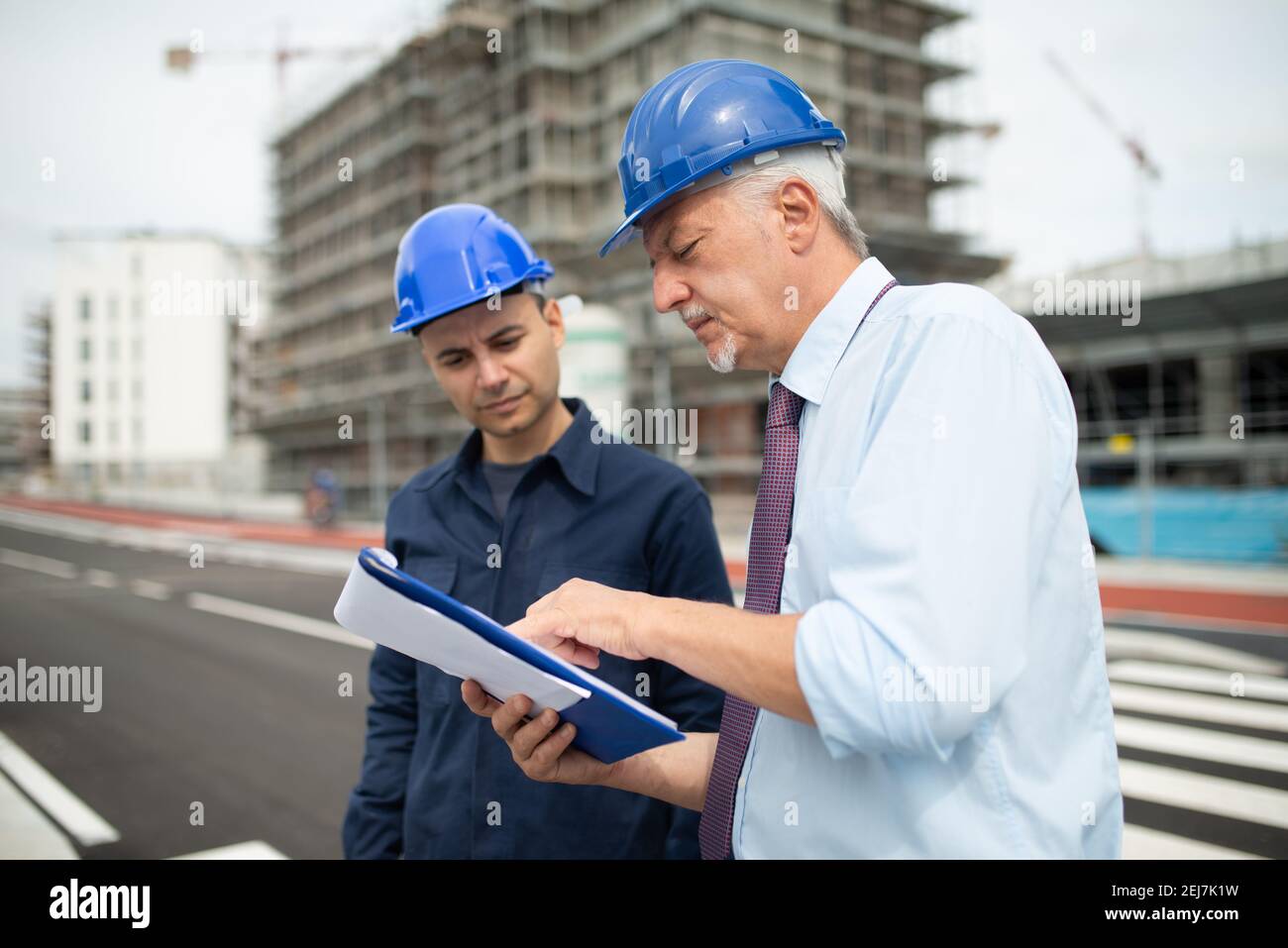Two architect developers reviewing building plans at construction site ...