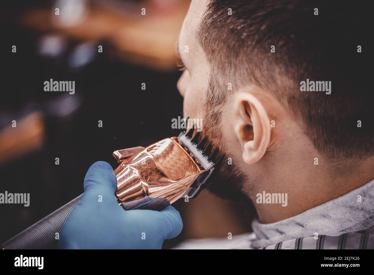 Close-up of barber with medical gloves shearing beard to man in ...