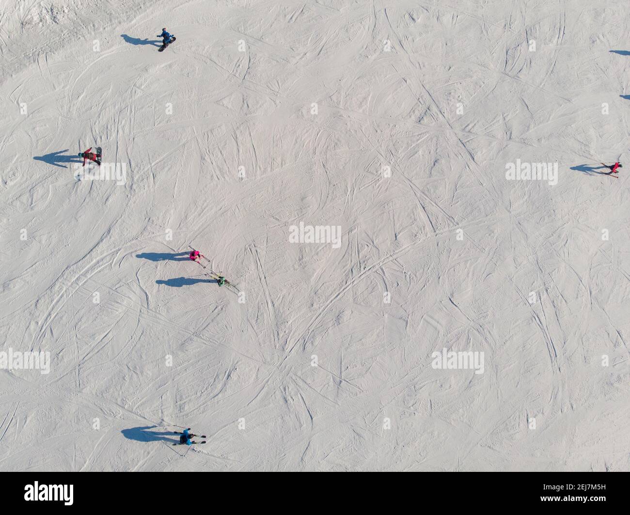 Snowboarders and skiers drive down ski slope in winter through fresh ...