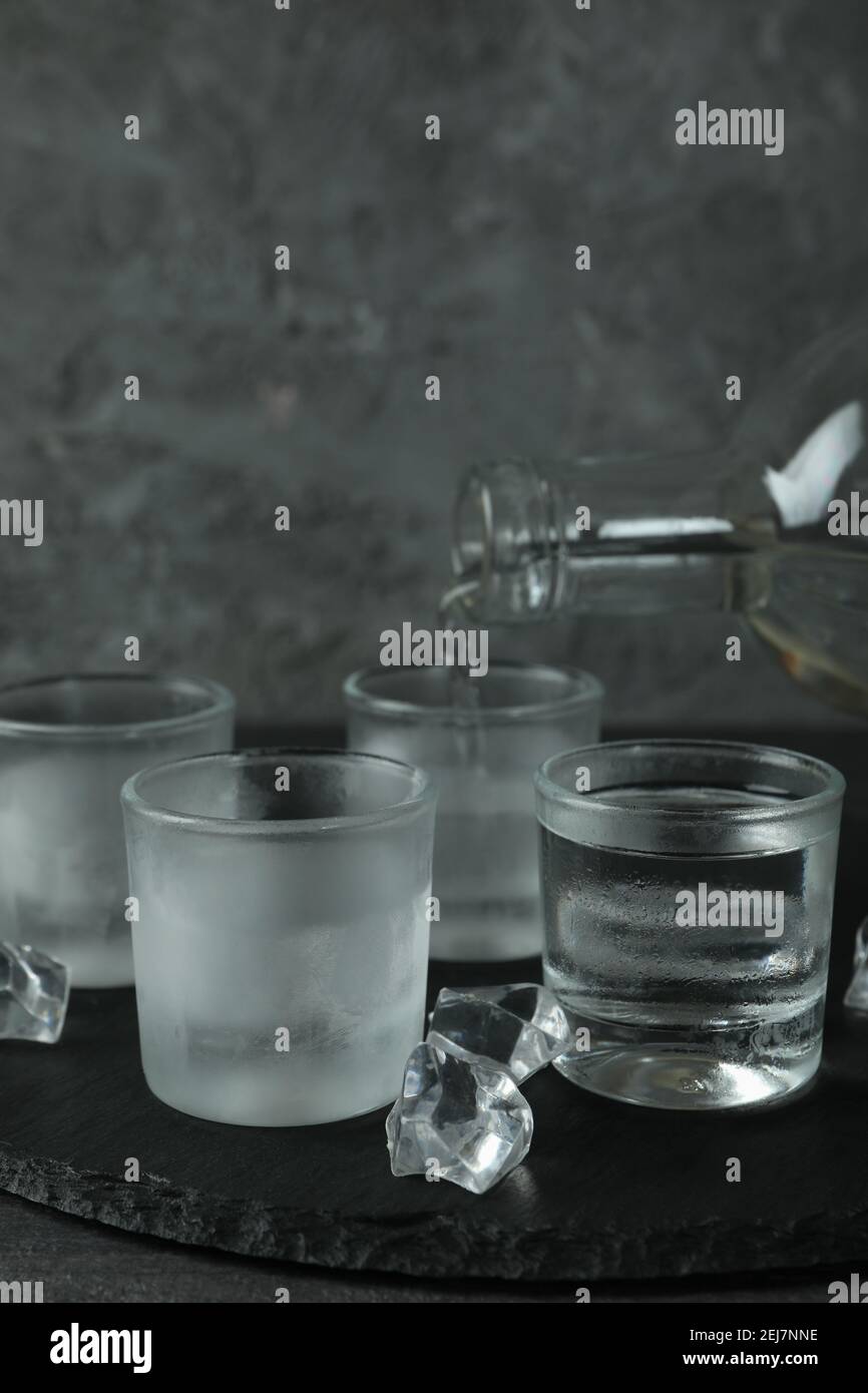 A bottle with pouring vodka and shots of vodka on black tray Stock ...