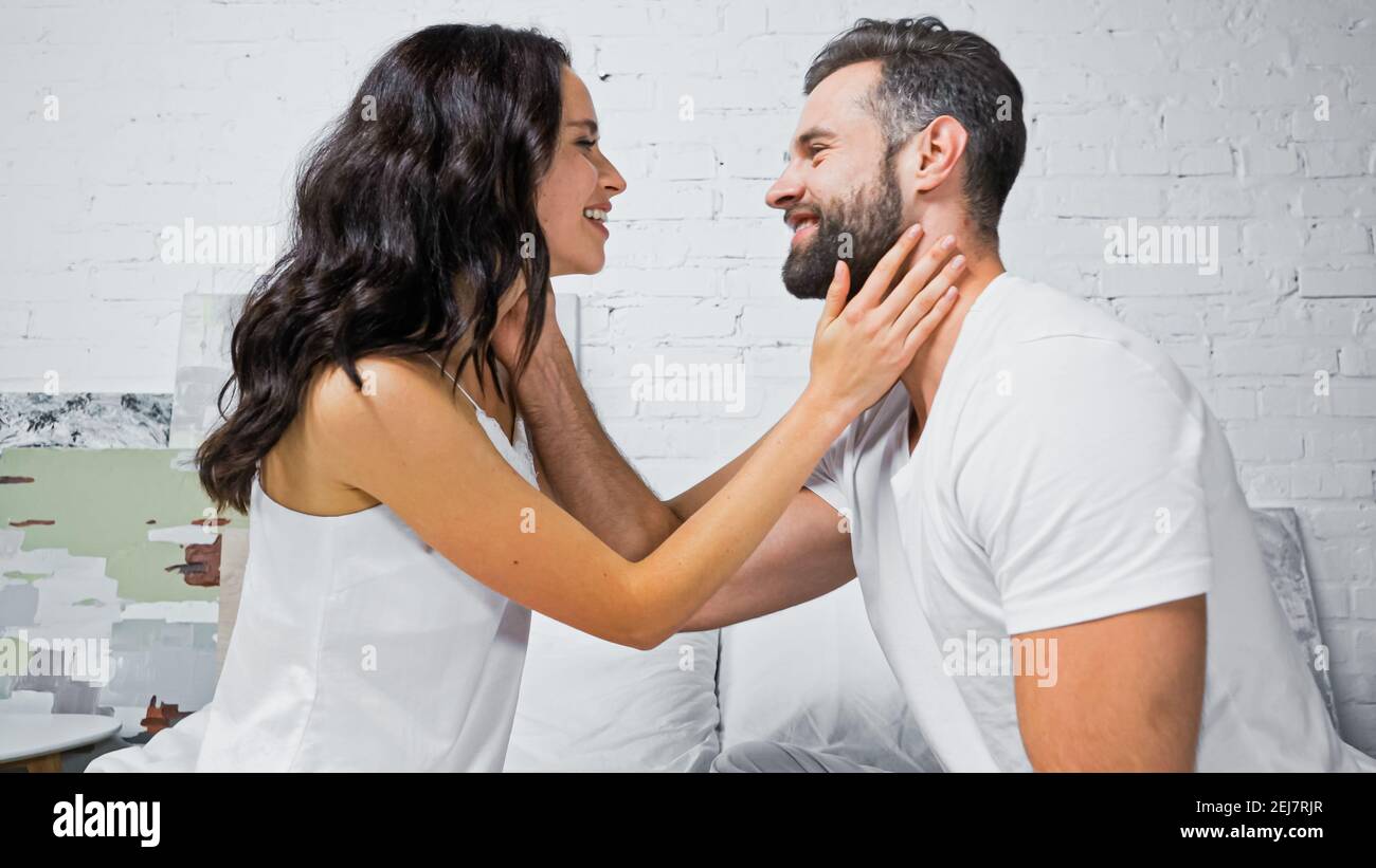 side view of happy brunette woman hugging neck of smiling boyfriend in ...