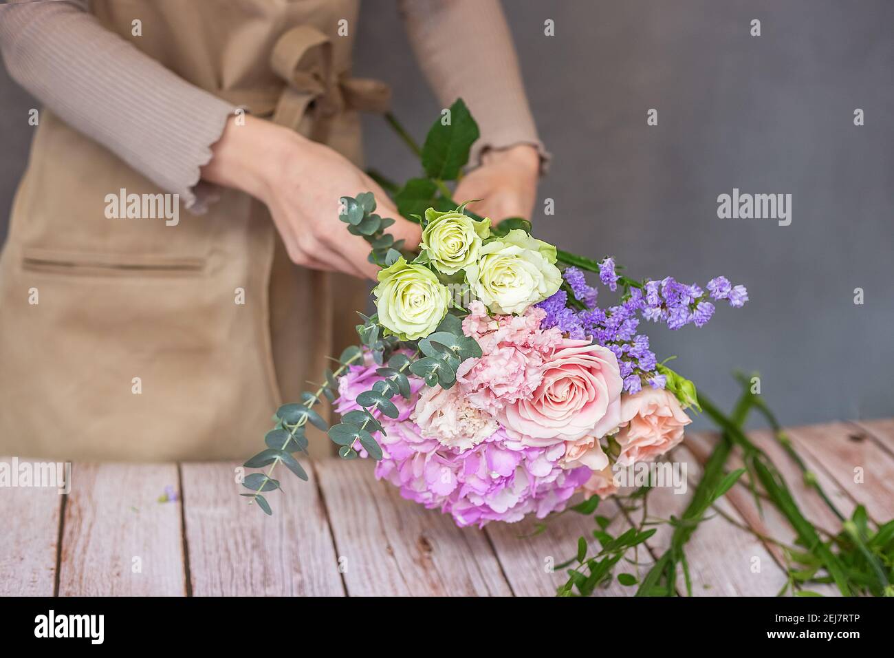 Florist at work. Female hands collect a romantic bouquet of roses ...
