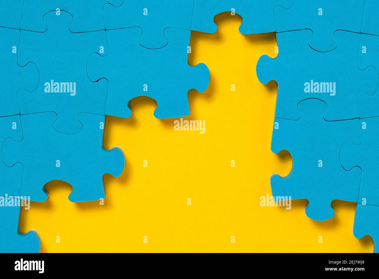 Unfinished blue jigsaw puzzle on yellow background with copy space ...