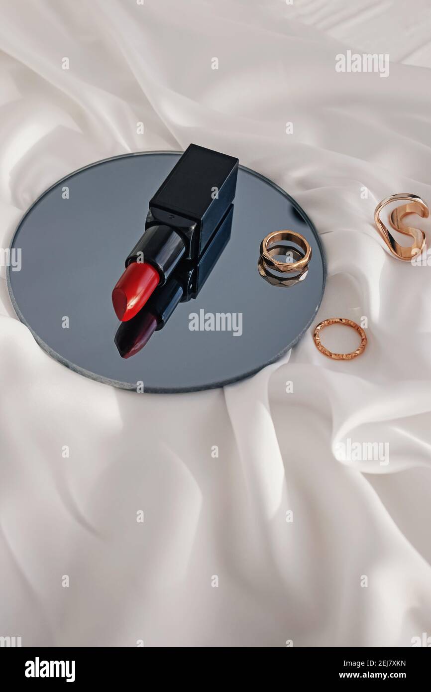 Red lipstick and golden rings on a round mirror Stock Photo - Alamy