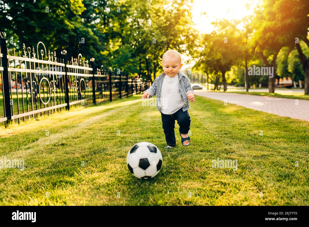 Athletic child. Happy little kid playing soccer ball in the park ...