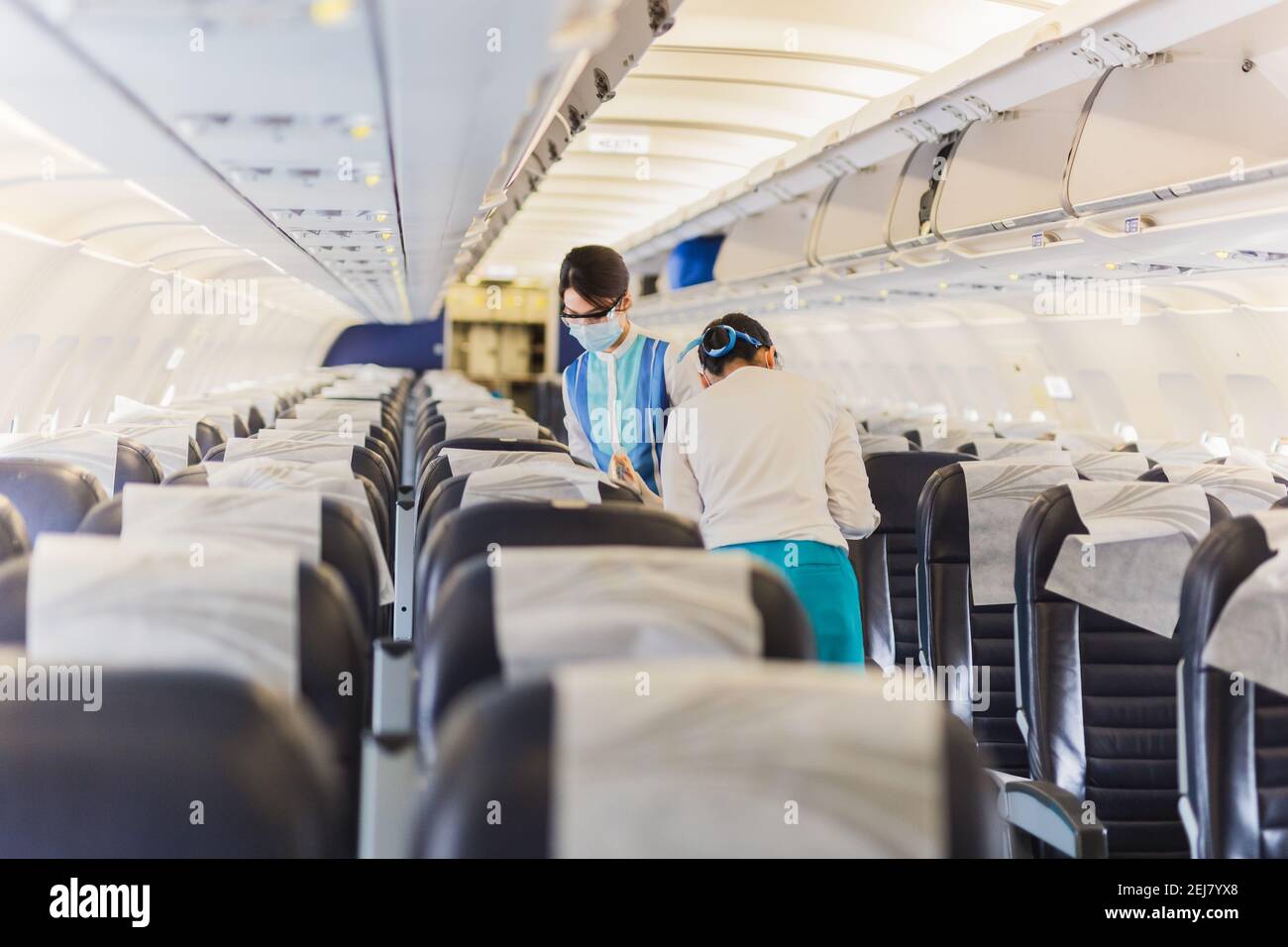 Flight attendant in face mask checking the passenger seat Stock Photo ...