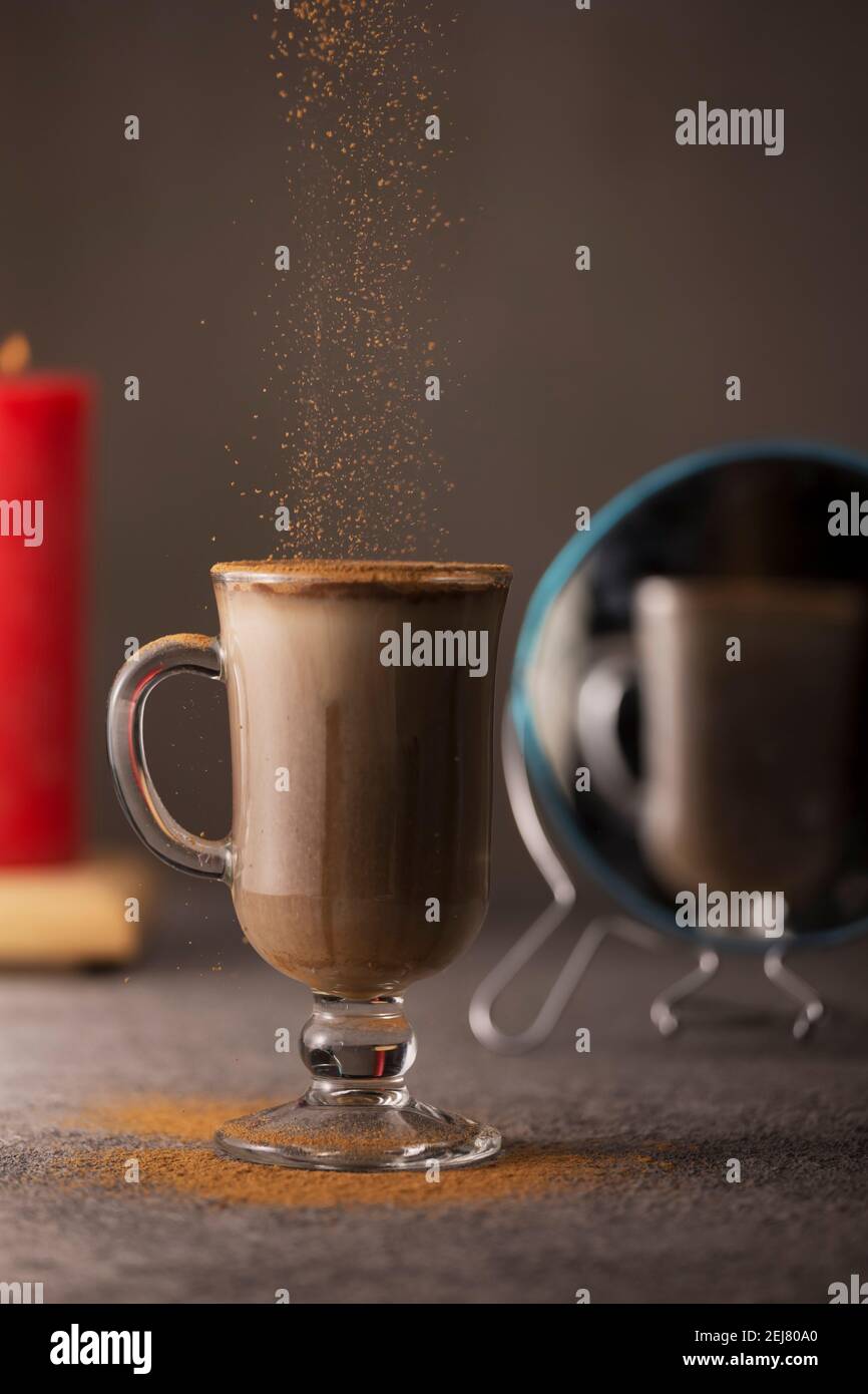 Sprinkle cinnamon powder over the hot chocolate Stock Photo - Alamy