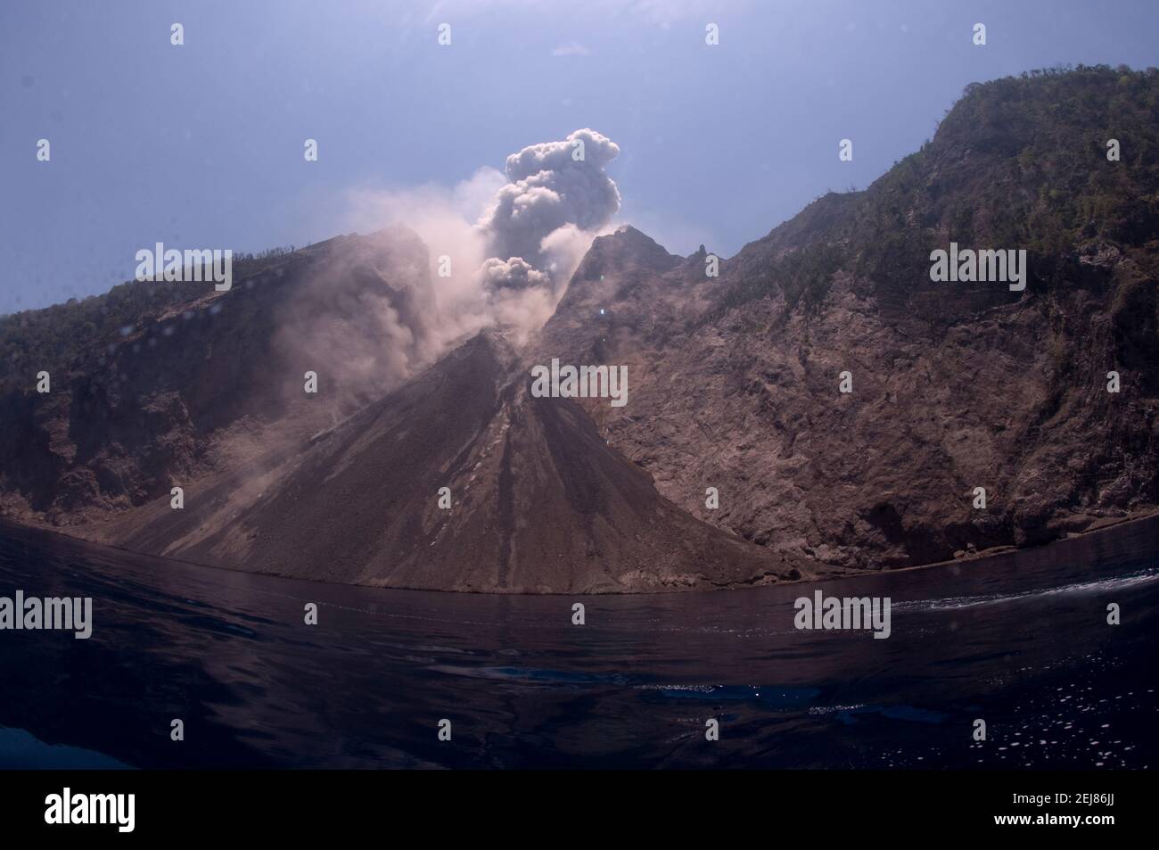 Volcano with ash plume and rocks bouncing down scree slope into sea ...