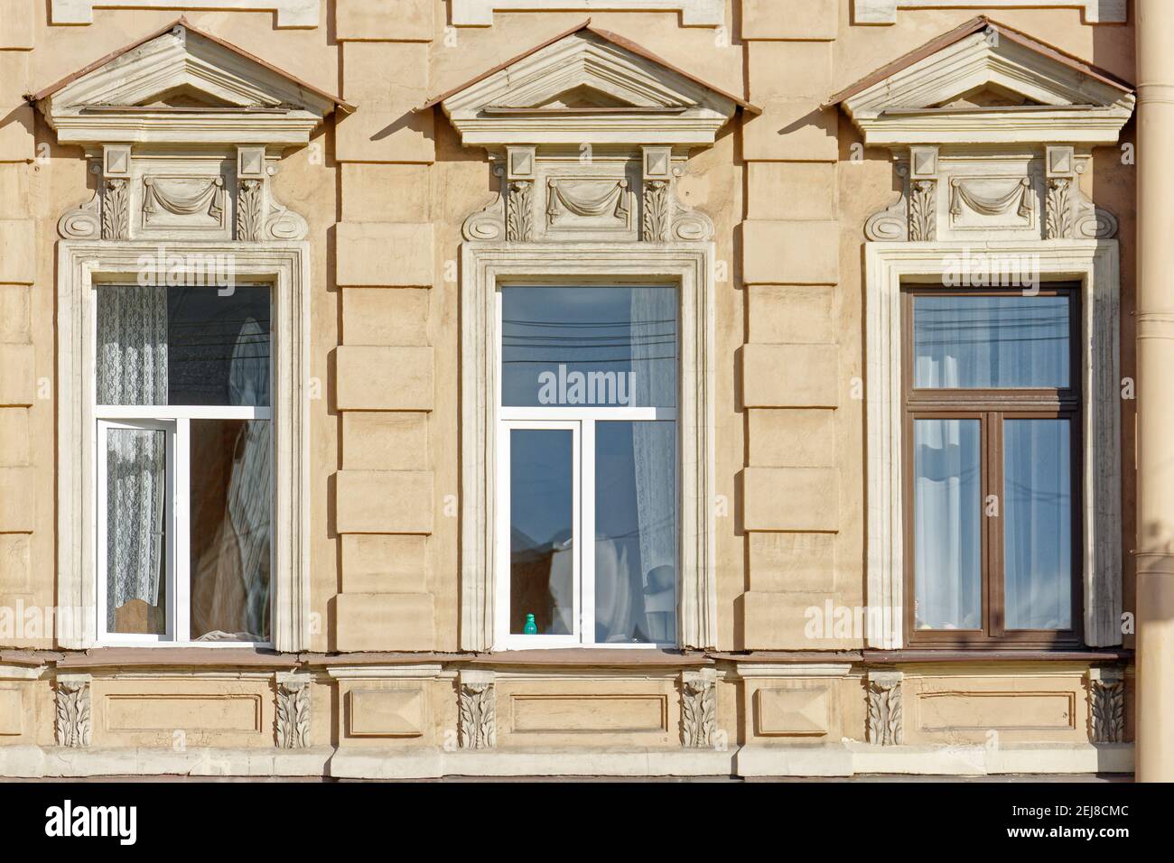 Three rectangular windows with a triangular visor and stucco moldings ...