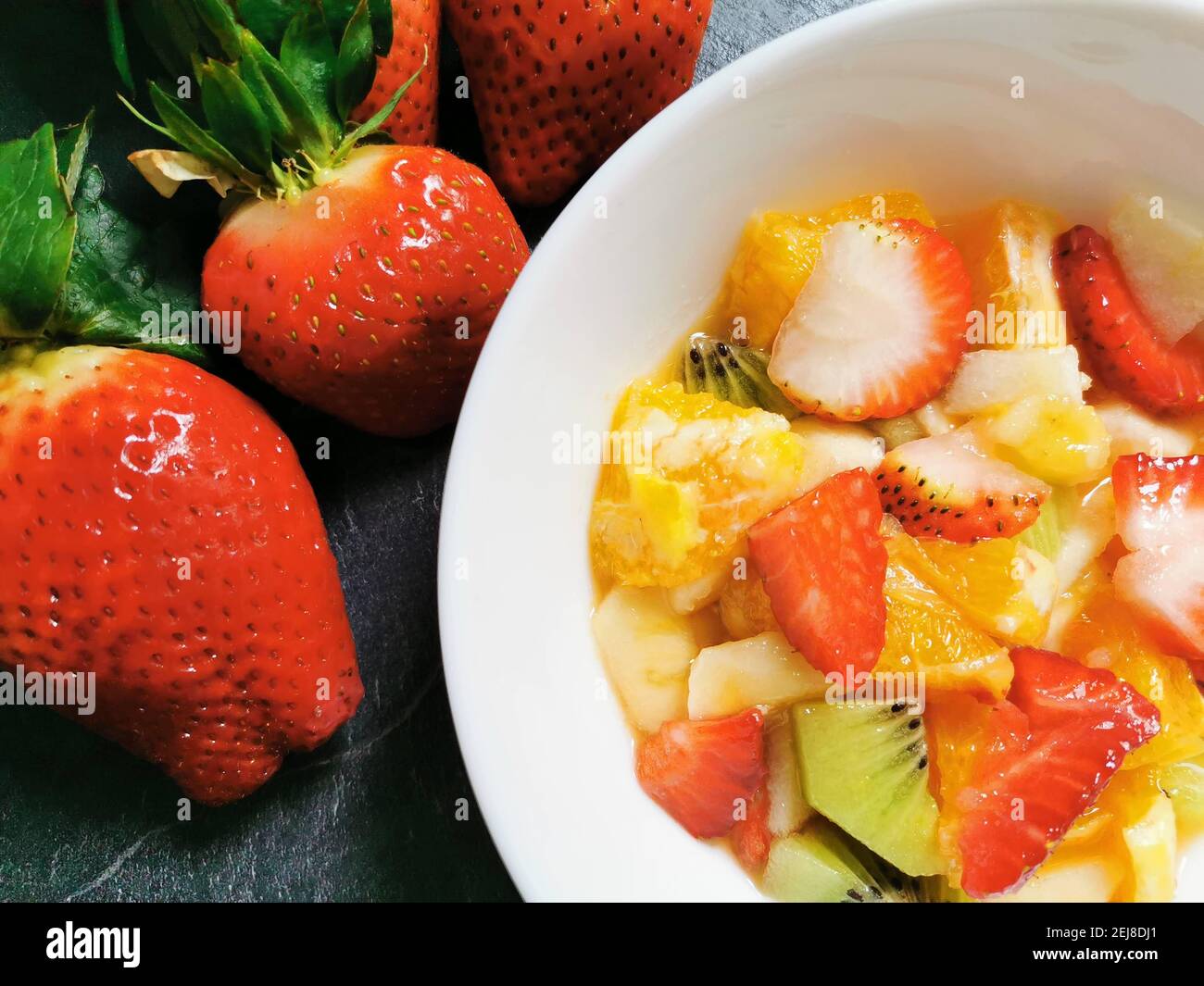 Bowl of fresh fruit salad surrounded by assortments of freshly prepared ...