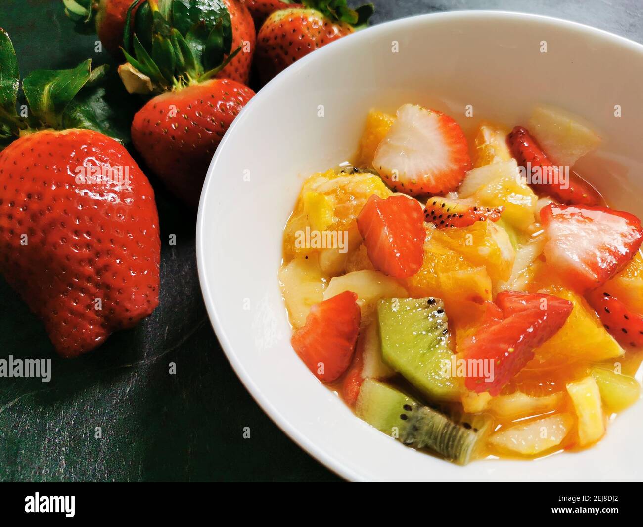 Bowl of fresh fruit salad surrounded by assortments of freshly prepared ...