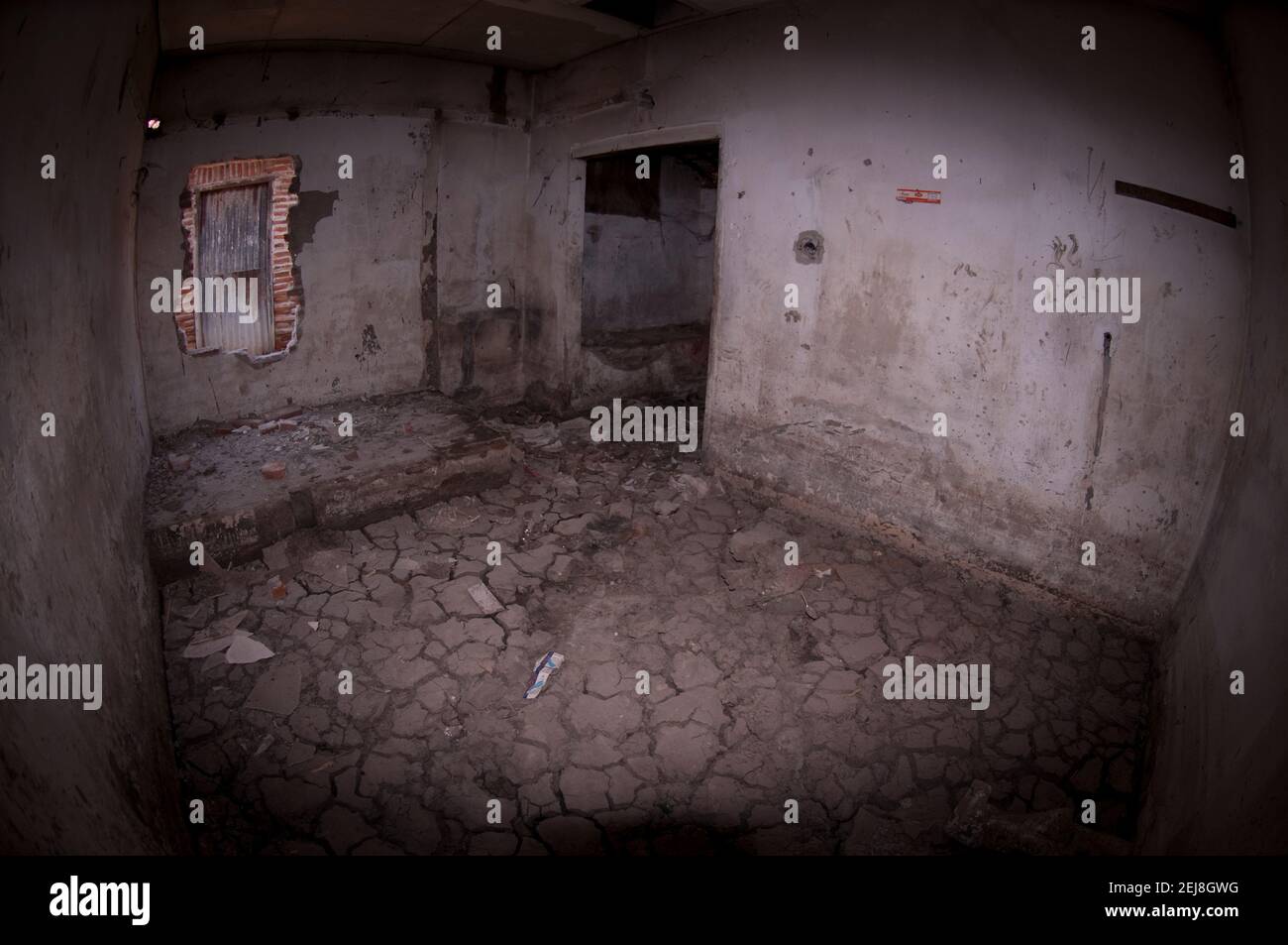 Abandoned house with dried mud on floor following flooding by mud lake ...