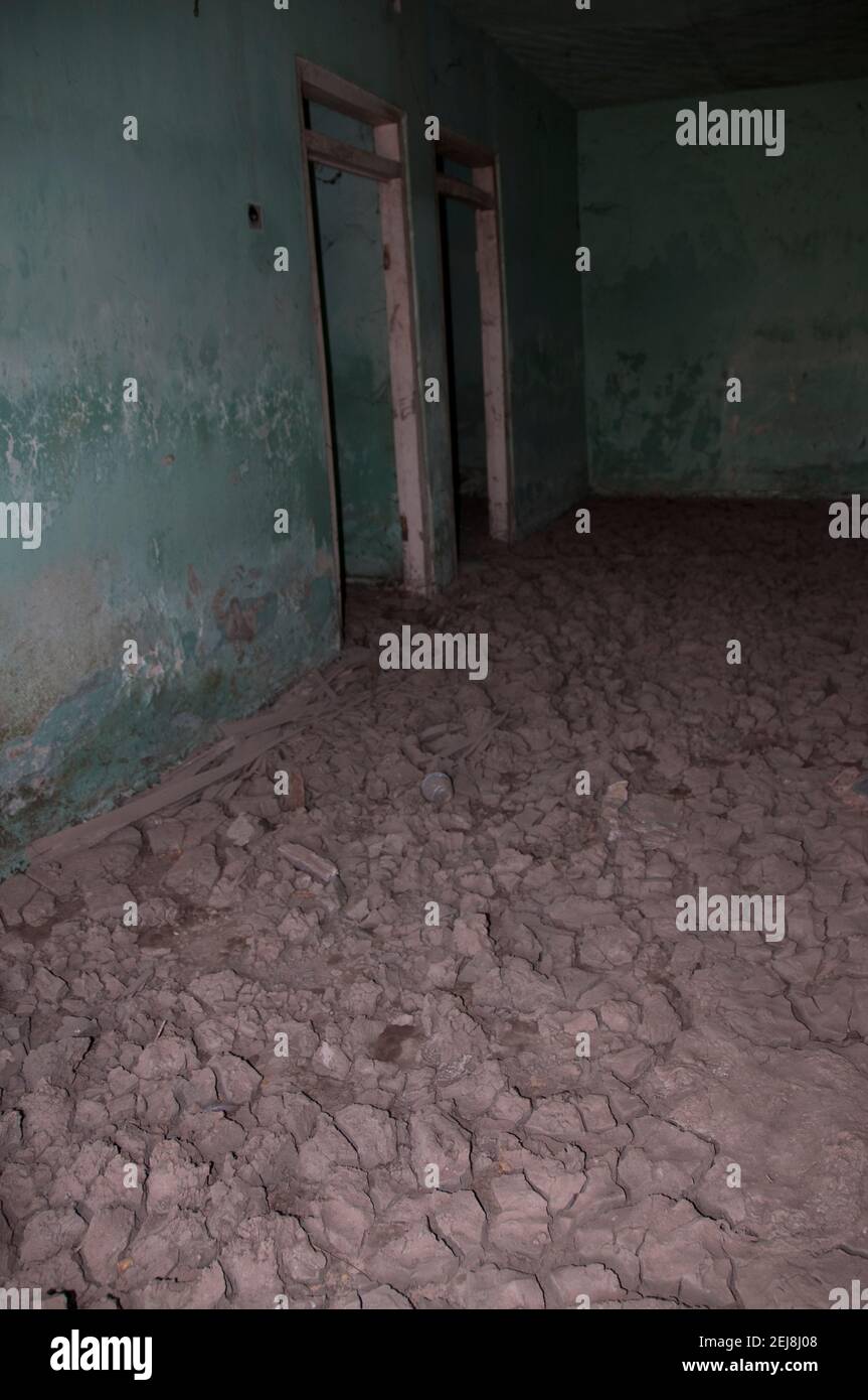 Abandoned house with dried mud on floor following flooding by mud lake ...