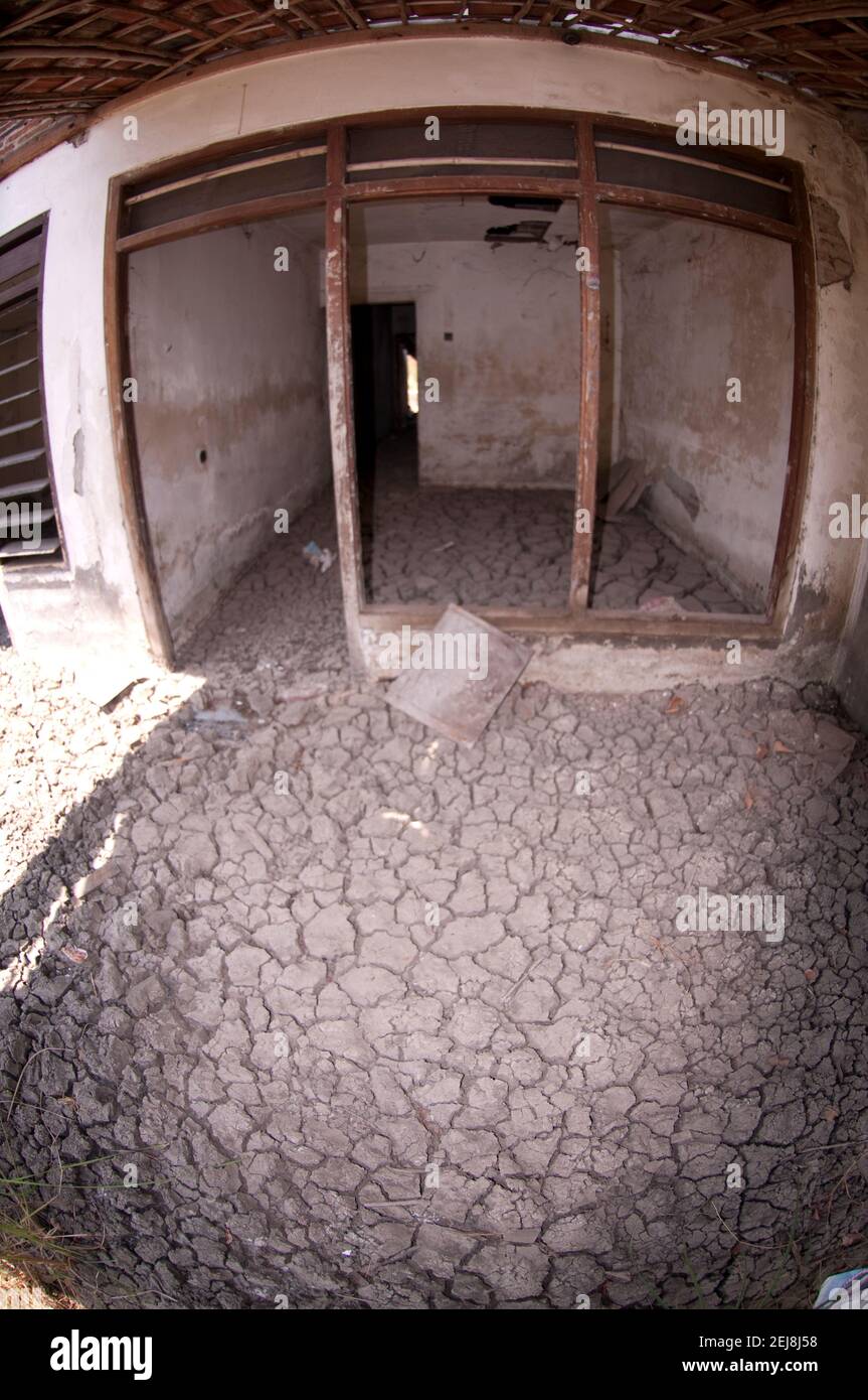 Abandoned house with dried mud on floor following flooding by mud lake ...