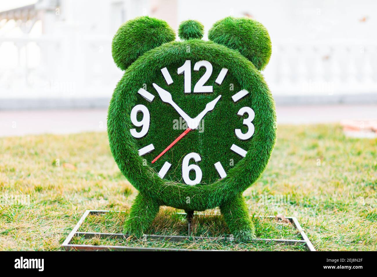 Landscape design. Green alarm clock made of artificial grass. The ...