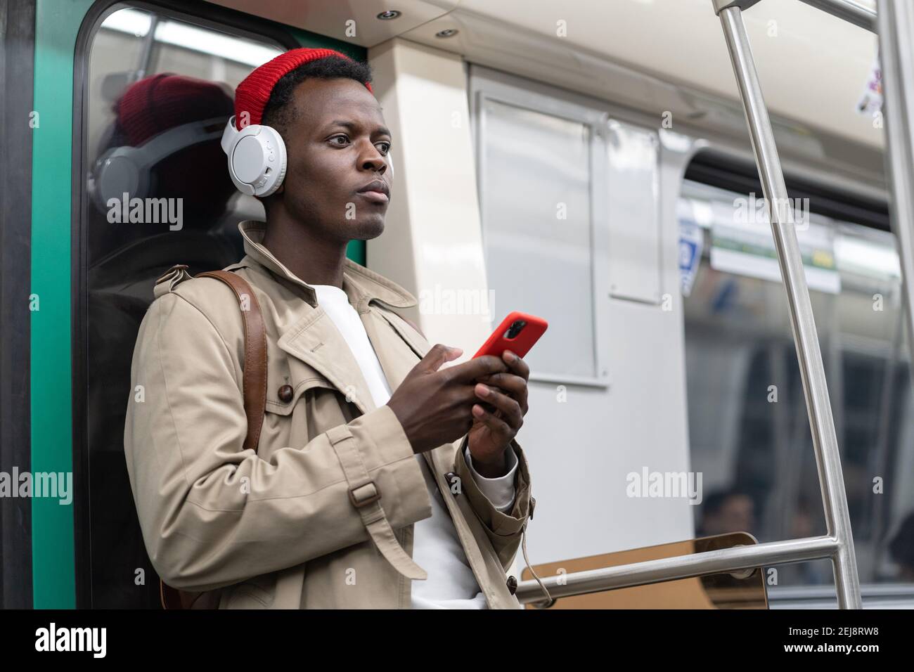 Pensive Black man in subway train thinking using cellphone listens to ...