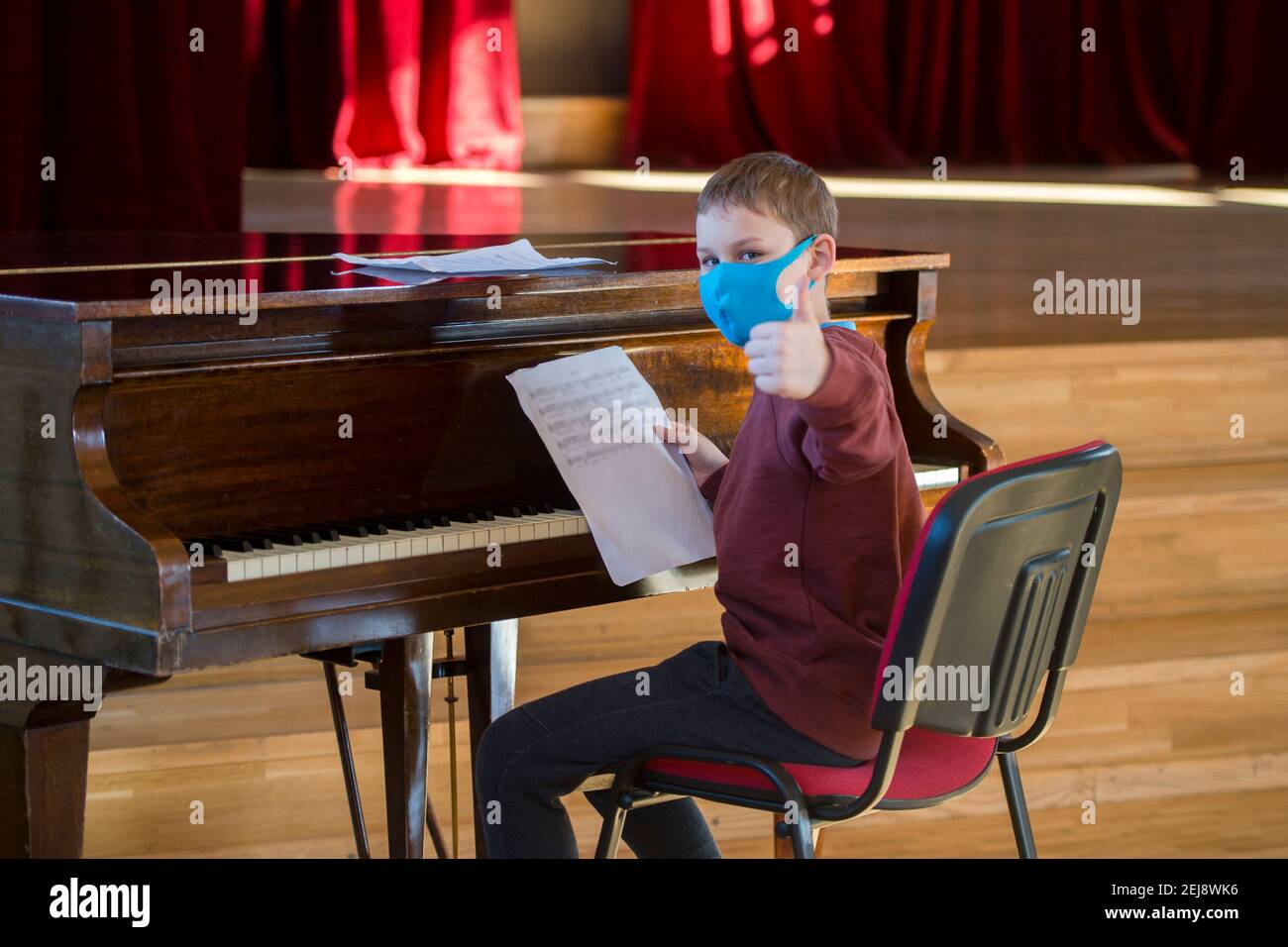 Boy wearing a blue mask and playing the piano at lesson and event. Kids ...
