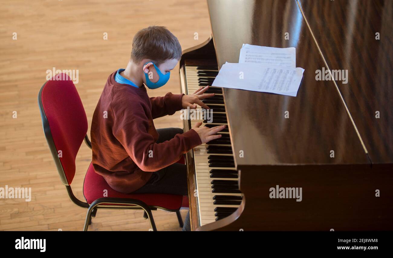 Boy wearing a blue mask and playing the piano at lesson and event. Kids ...