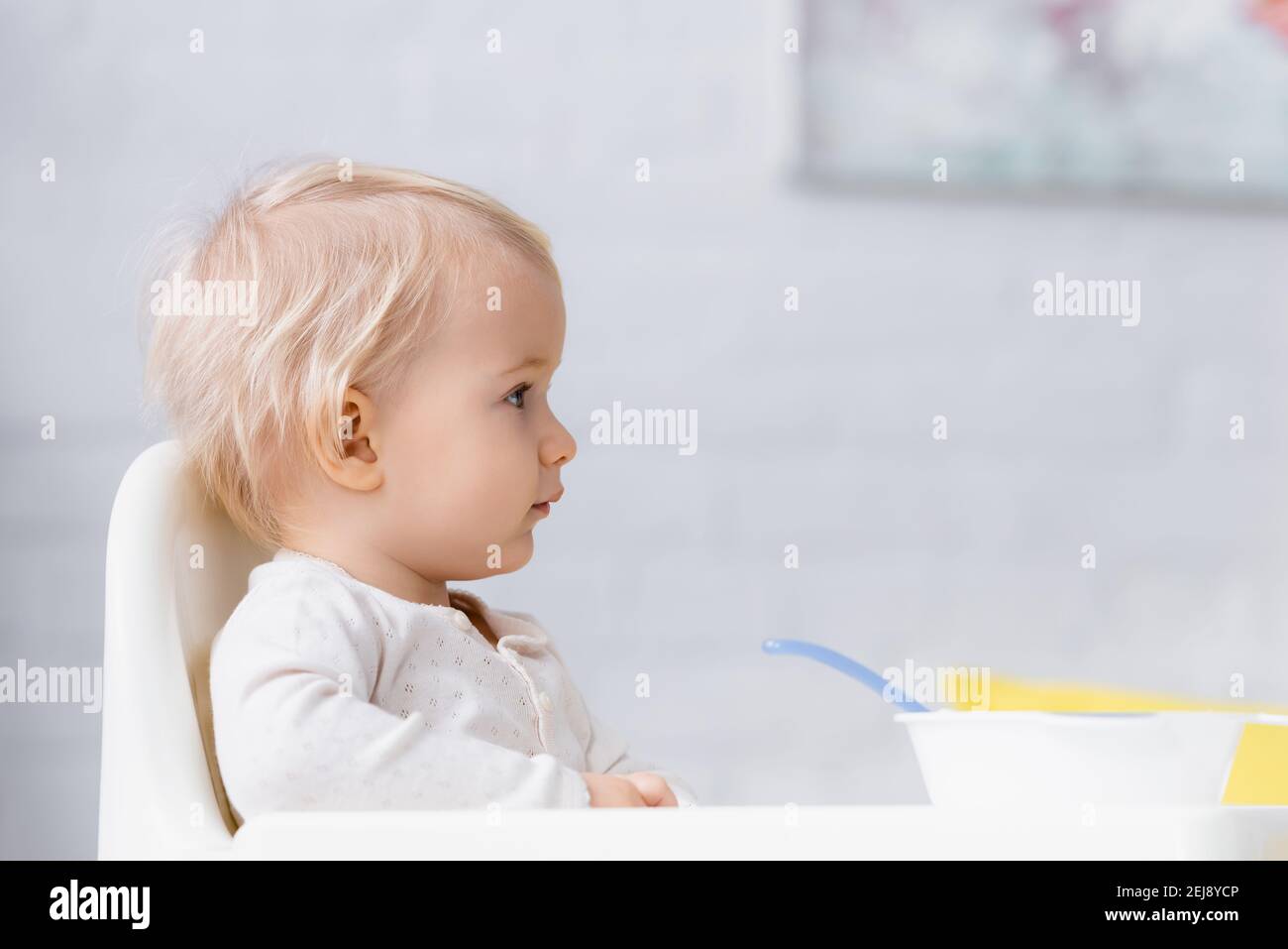 side view of little boy sitting on baby chair near bowl Stock Photo - Alamy