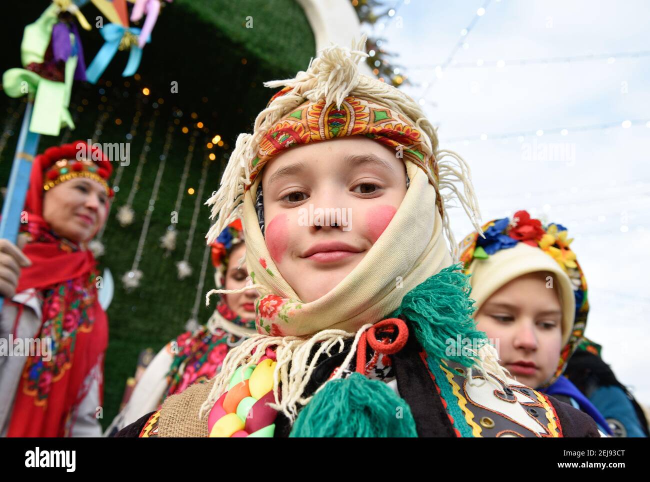 A boy dressed in a traditional costume sings Christmas carols. Members ...