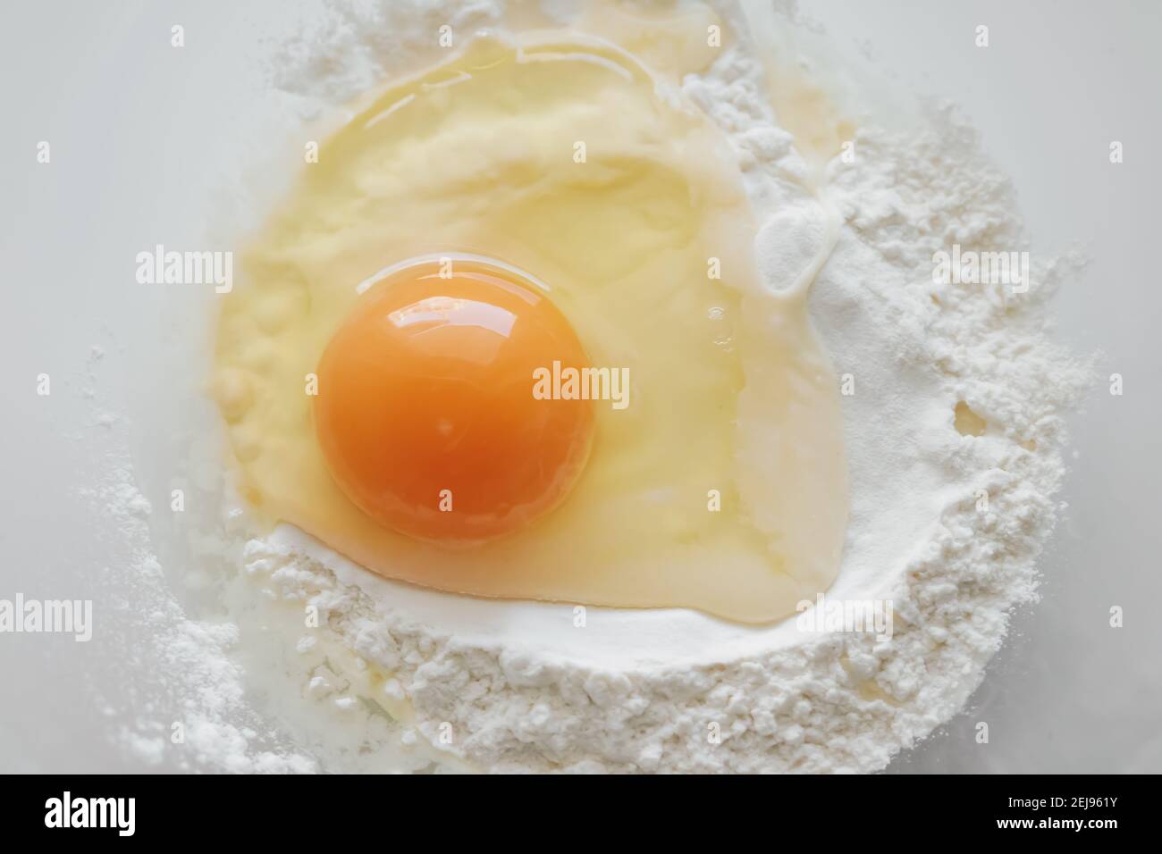 Raw egg and flour, preparing batter for baking process Stock Photo - Alamy