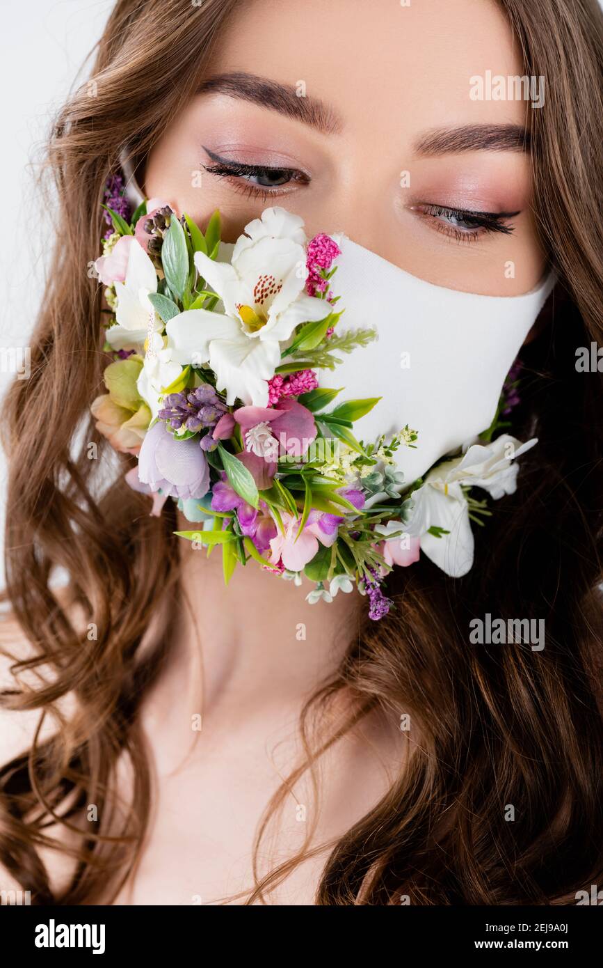 Portrait of young woman in medical mask with flowers and leaves ...