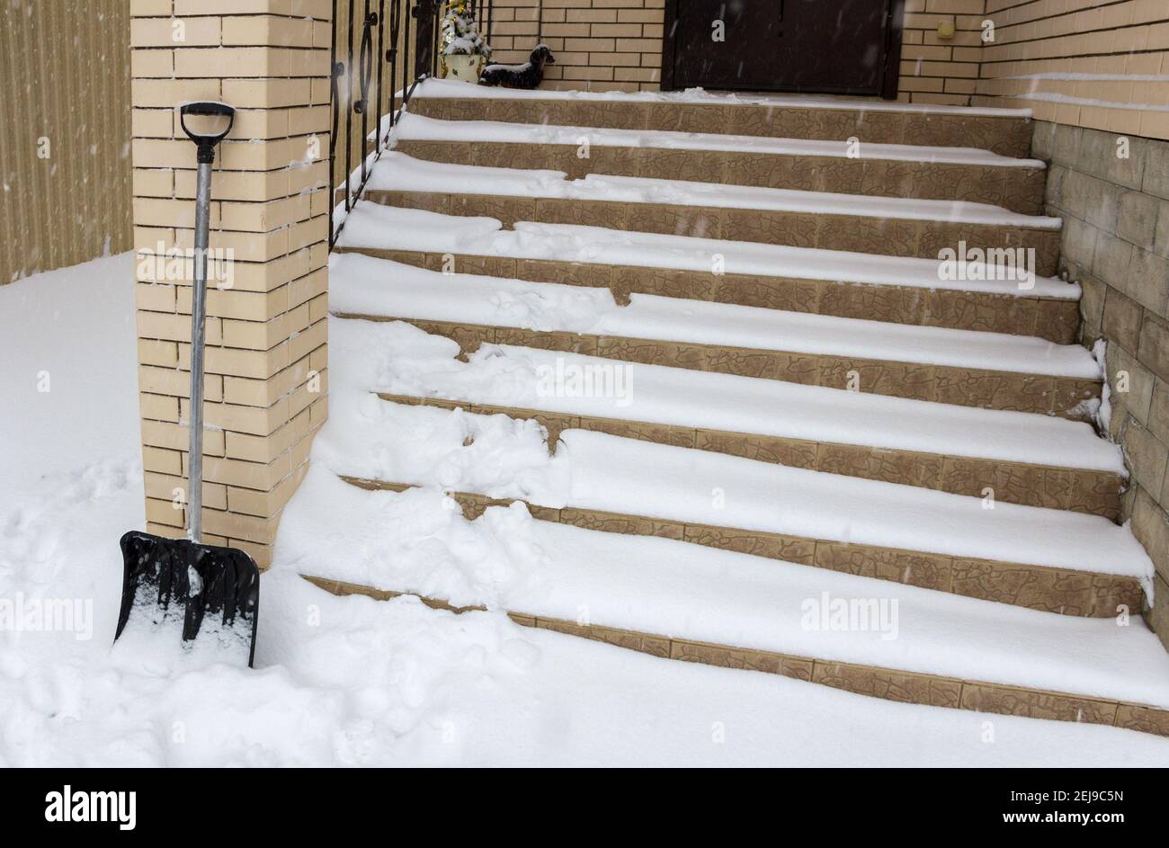 Light brick porch of a private house covered with snow, footprints on ...