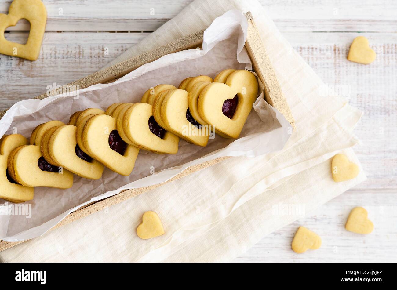 Vanilla and raspberry jam heart shaped cookies in a wooden box with a ...
