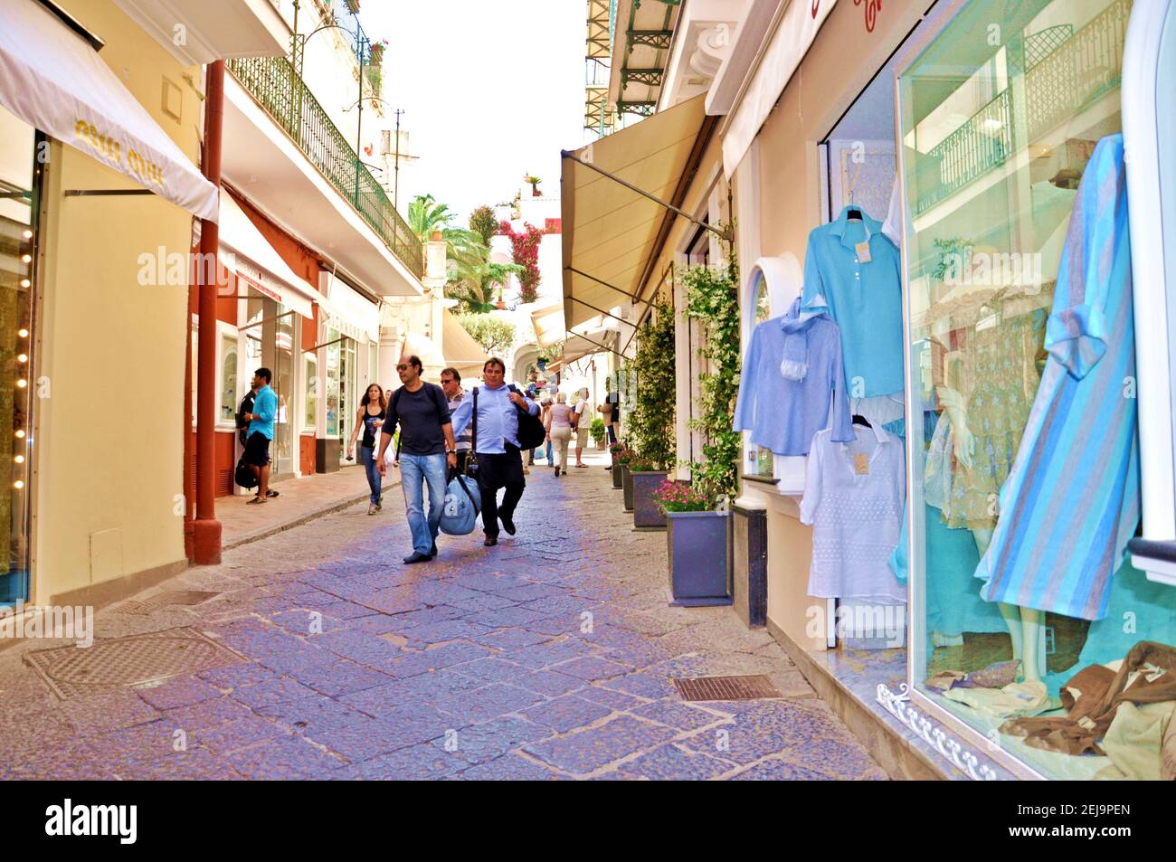 People walking on the shopping narrow street with shops on the left and ...