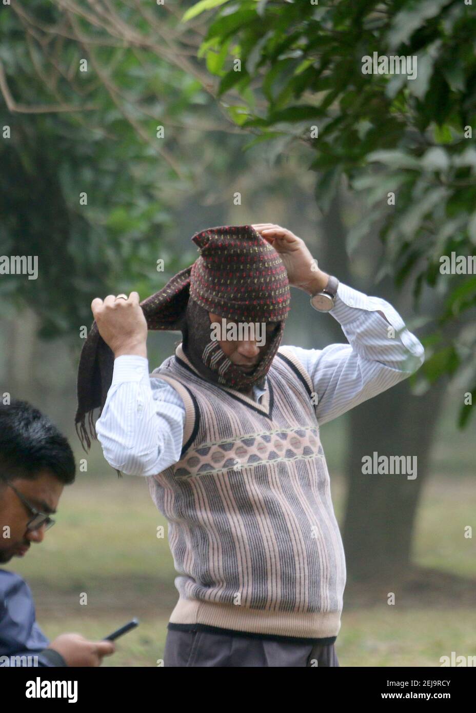A man wraps a piece of cloth around his head during the cold weather in ...